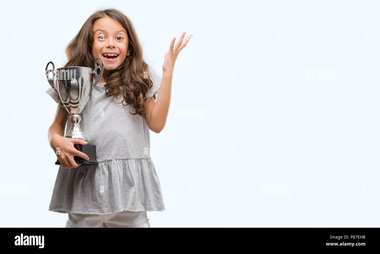 Brunette hispanic girl holding a trophy very happy and excited, winner ...
