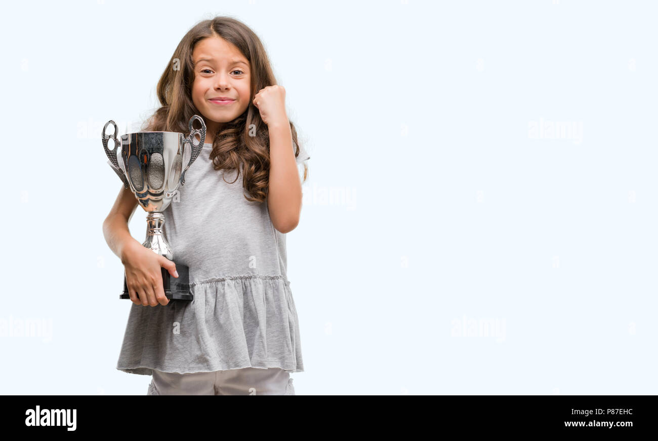 Brunette hispanic girl holding a trophy screaming proud and celebrating ...