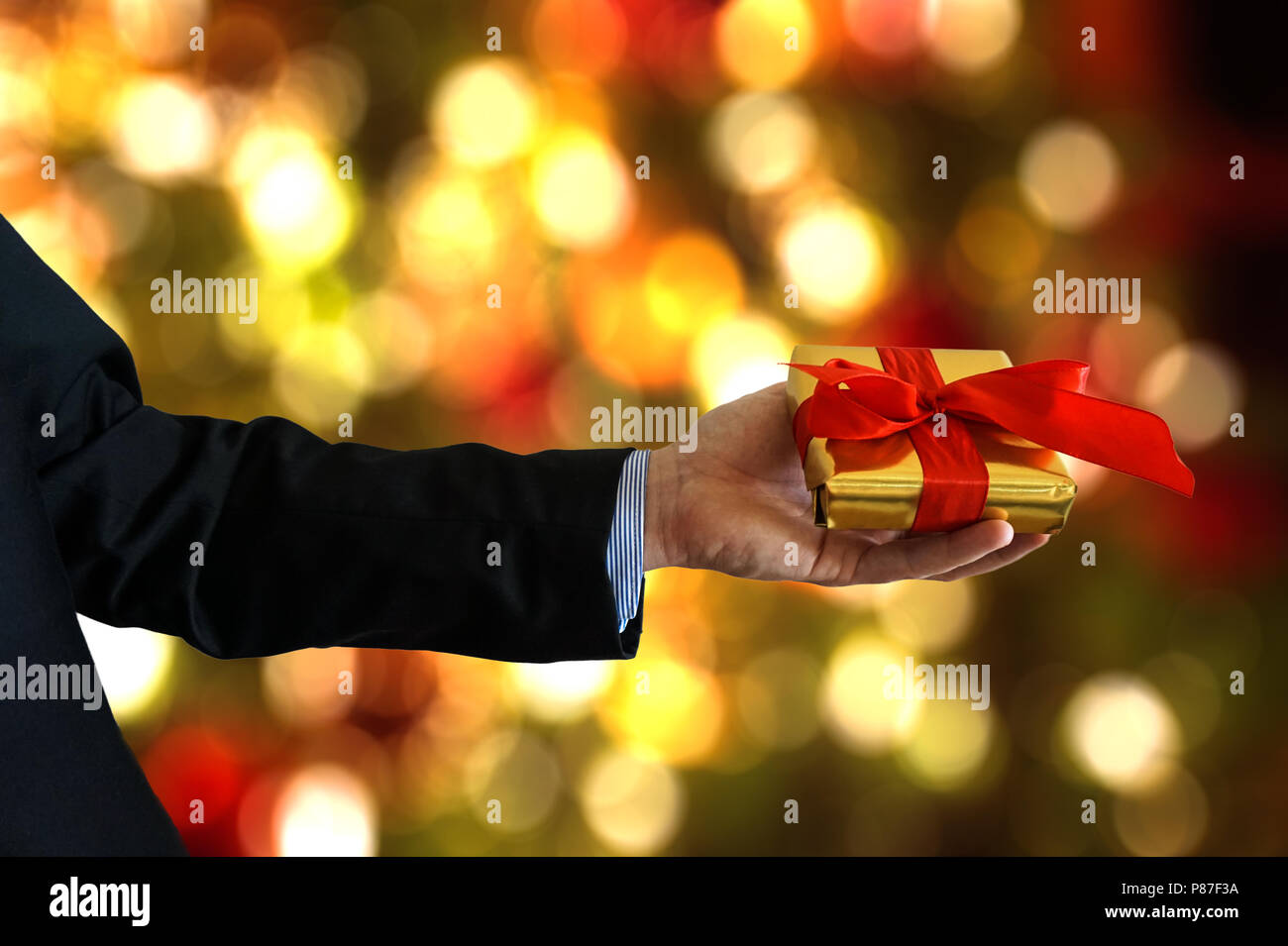 Man giving a present in suit with cristmas lights Stock Photo - Alamy
