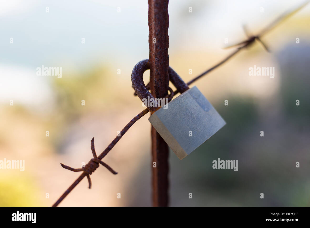 Old and Rusty padlock on a steel pole with barbed wire locked Stock ...
