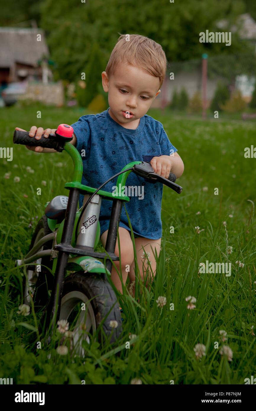 A cute little boy with a bicycle near the house, a sport for children ...