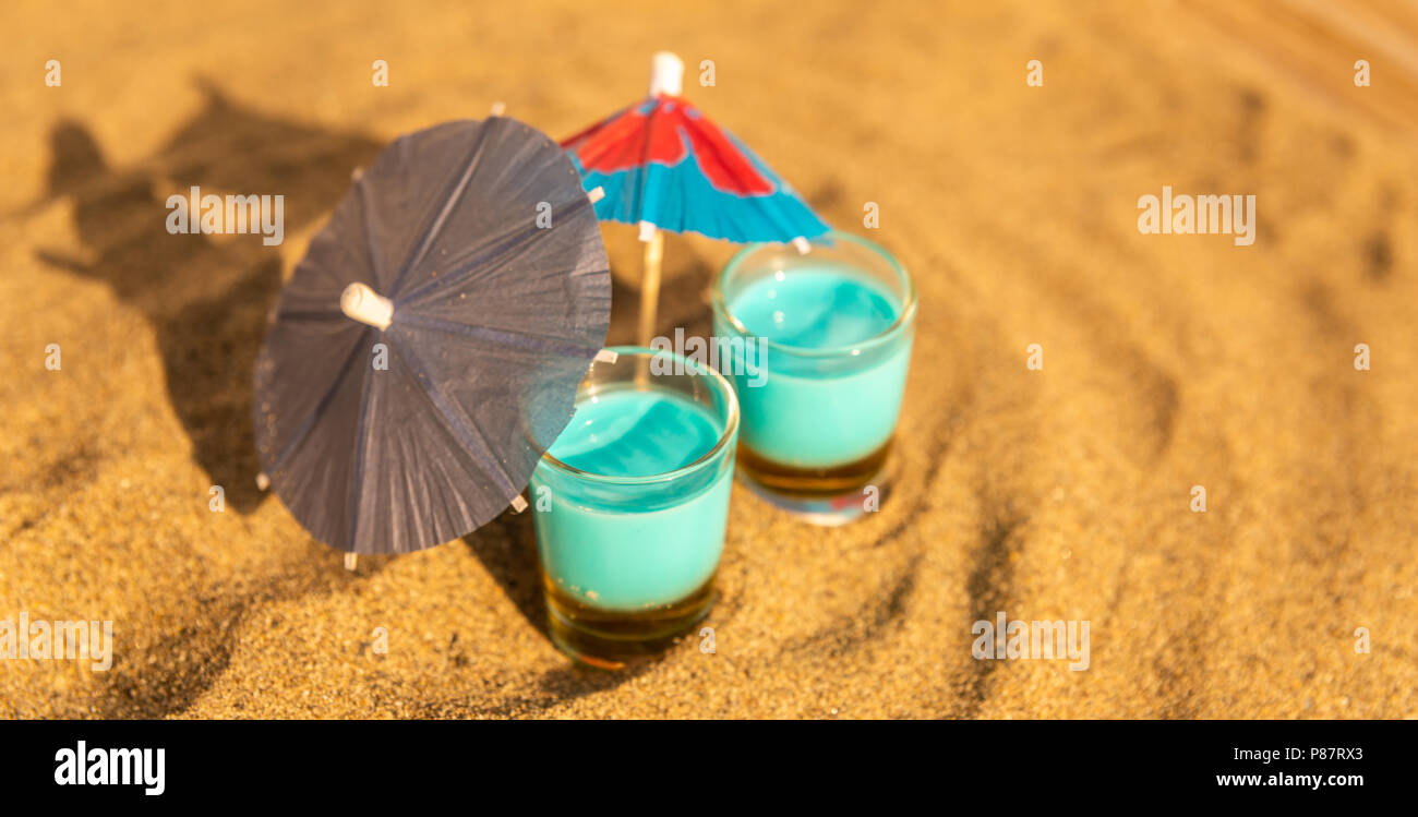 colorful shots drinks on a sandy beach with umbrellas for drinks ...
