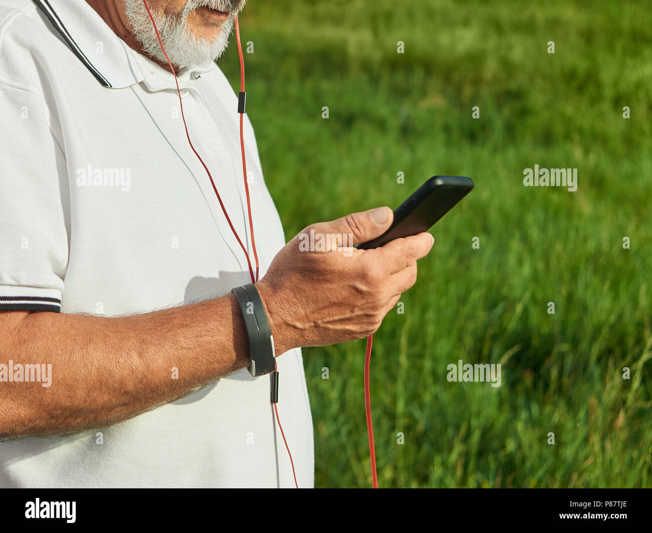 Cropped photo of old man checking time while running outside. Keeping ...