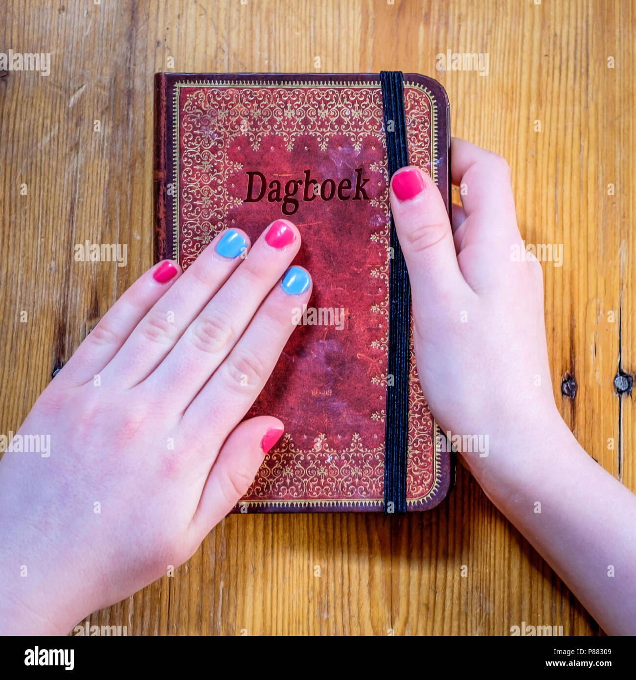 Young girl holding her hands on a vintage diary with the Dutch word ...