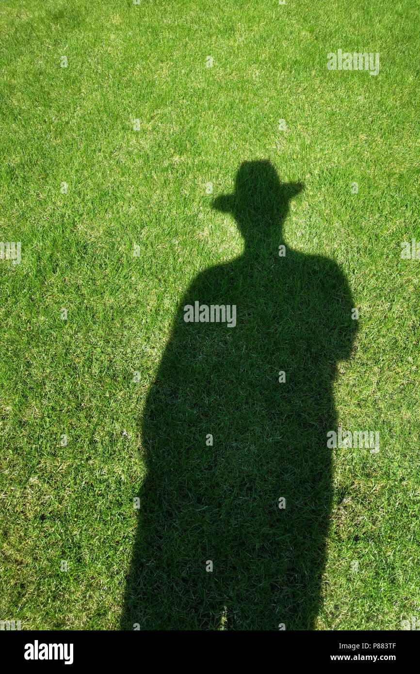 Shadow silhouette of man wearing hat on green grass lawn. Human shade ...