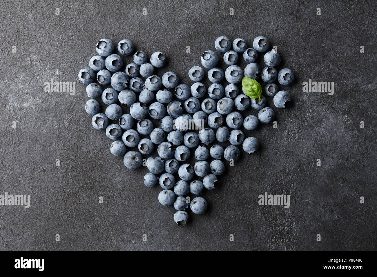 Fresh blueberries heart shape on black background. Healthy food eating ...