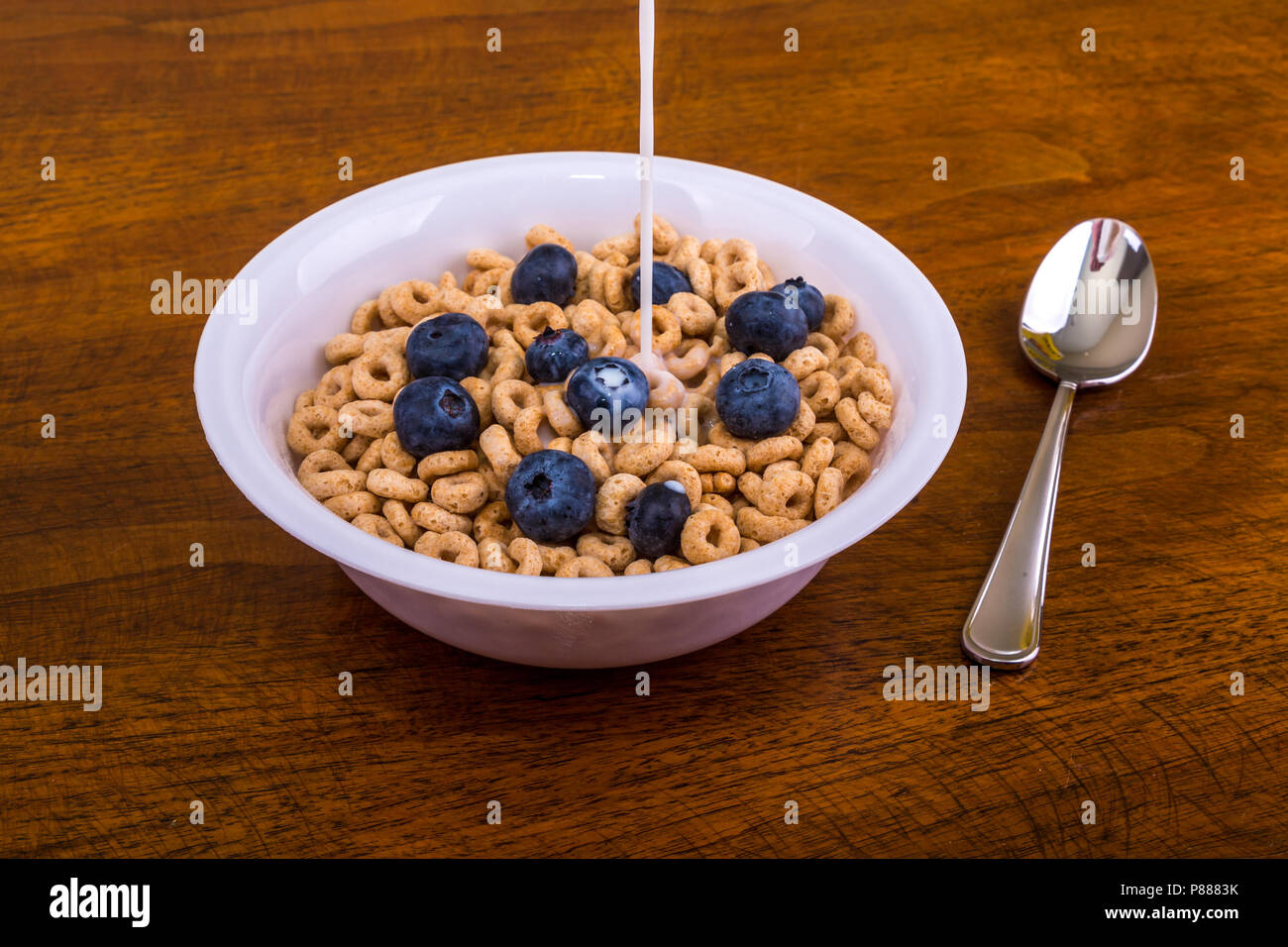 Pouring Milk on Oat Cereal with Blueberries Stock Photo - Alamy