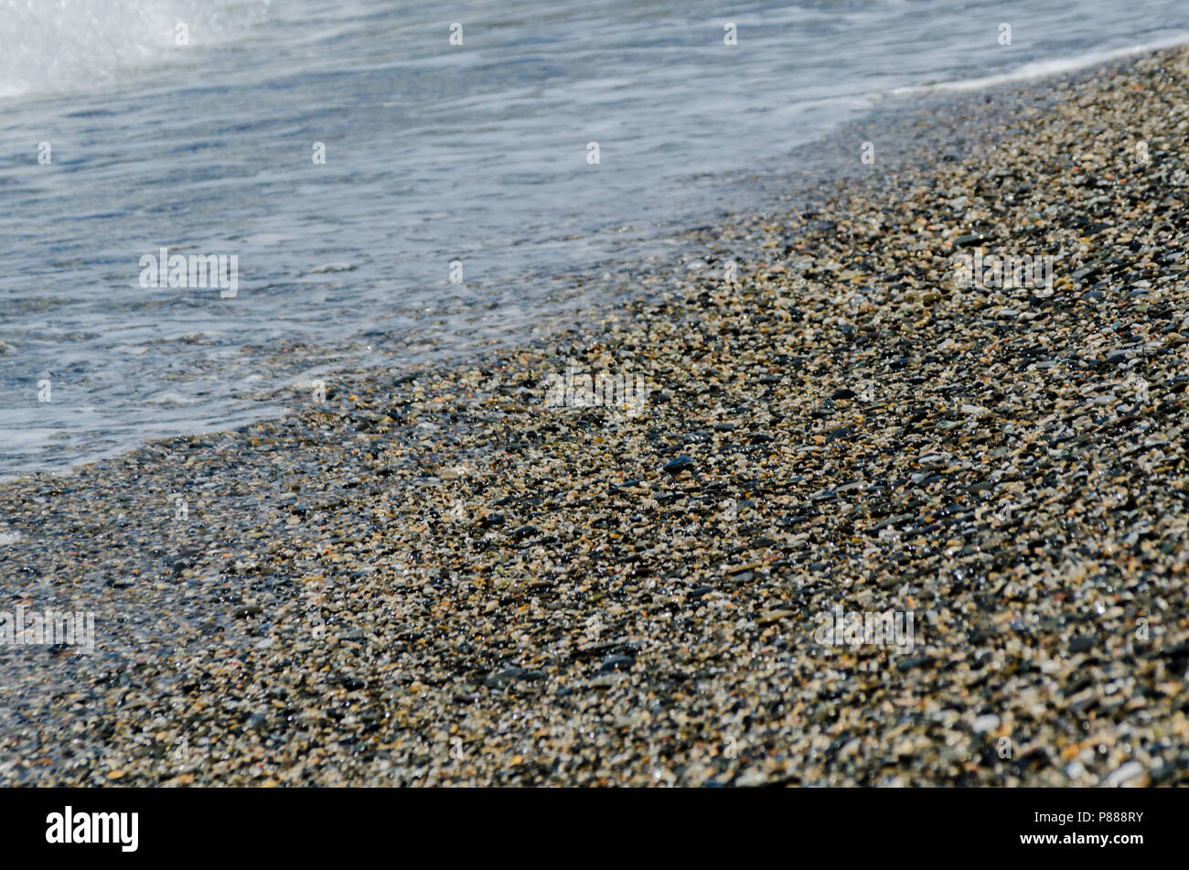 pebble beach washed by sea waves, small and various stones forming the ...