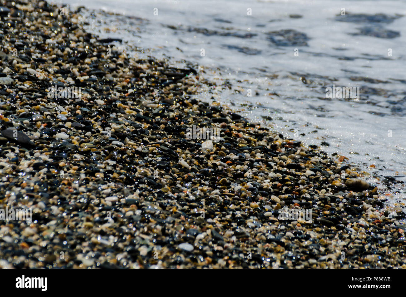 pebble beach washed by sea waves, small and various stones forming the ...