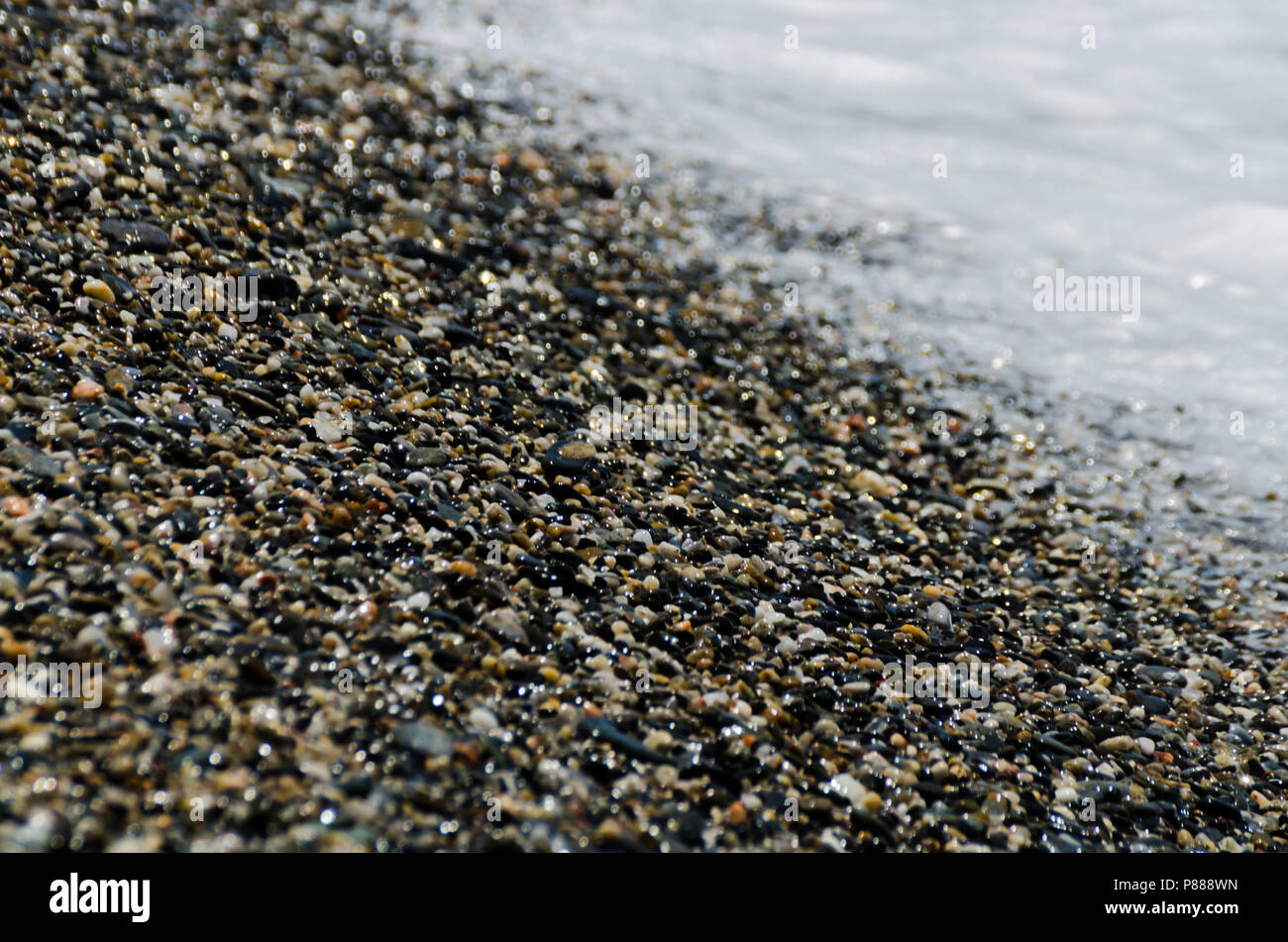 pebble beach washed by sea waves, small and various stones forming the ...