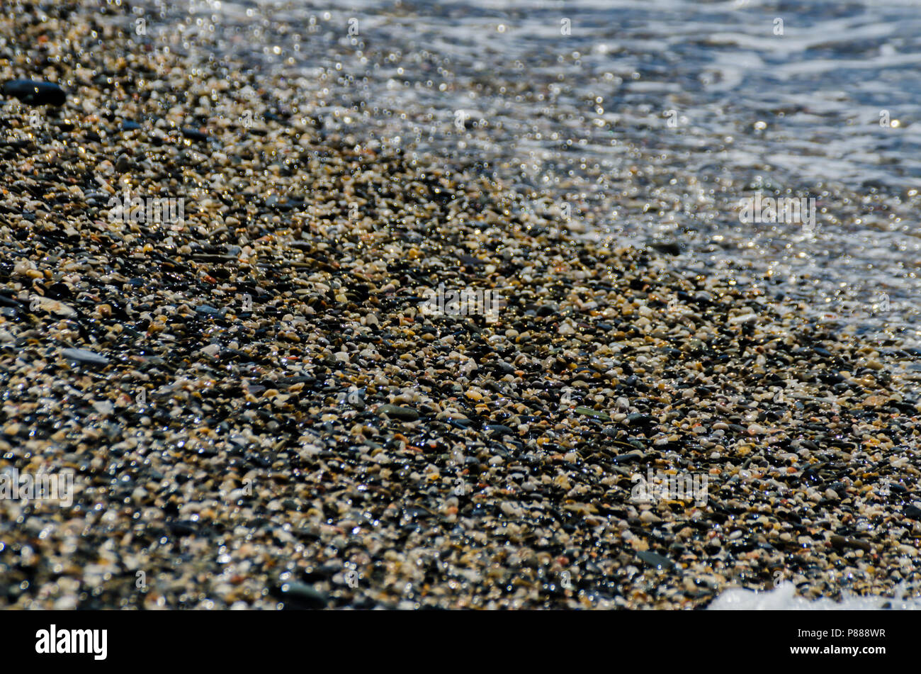 pebble beach washed by sea waves, small and various stones forming the ...