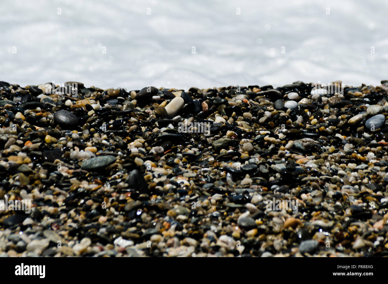 pebble beach washed by sea waves, small and various stones forming the ...