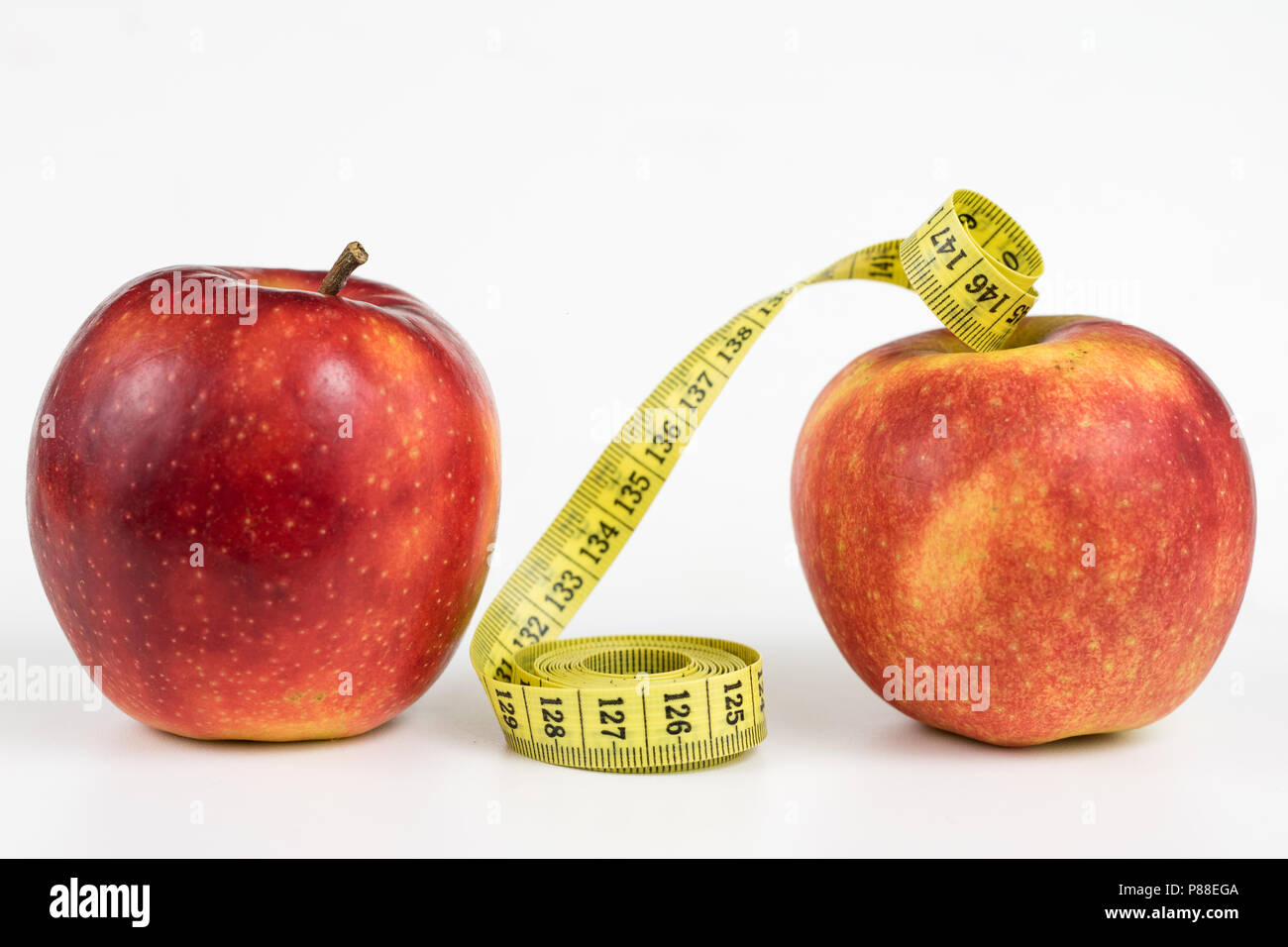 Red apples and a measure of tailor on a white table. Ripe fruits and a ...