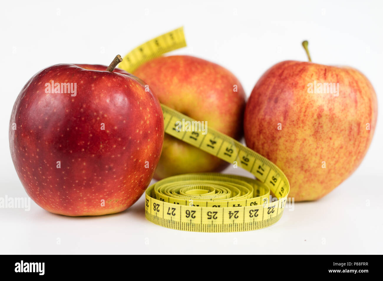 Red apples and a measure of tailor on a white table. Ripe fruits and a ...