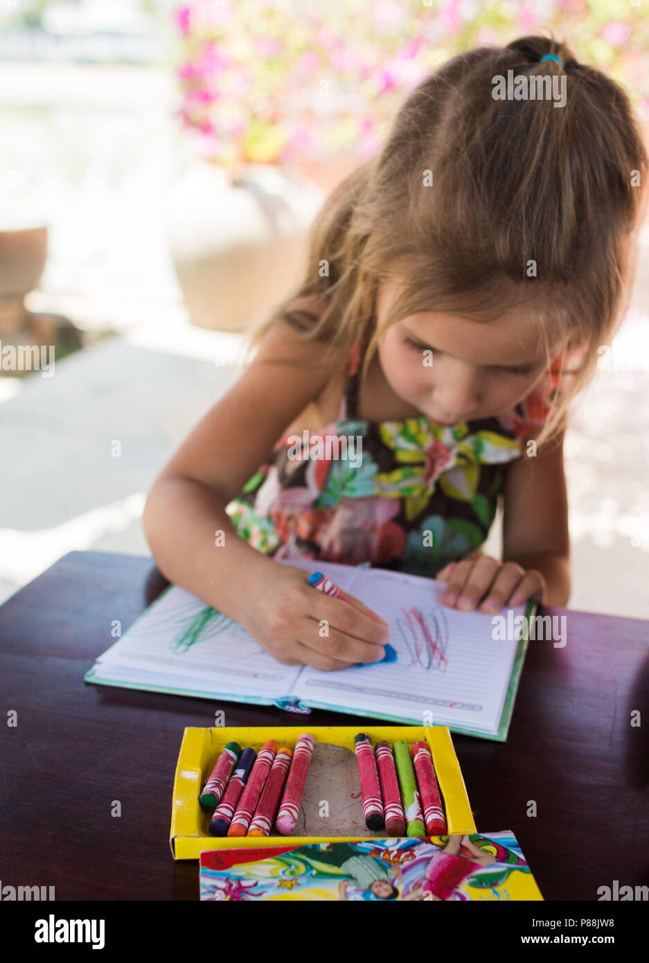 Adorable little girl drawing artwork top view on crayons in a notebook ...