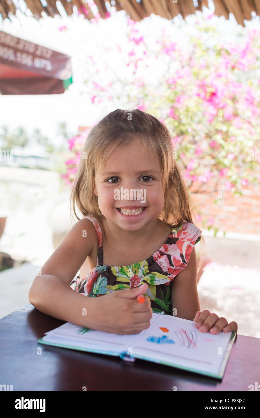 Adorable little girl drawing artwork top view on crayons in a notebook ...