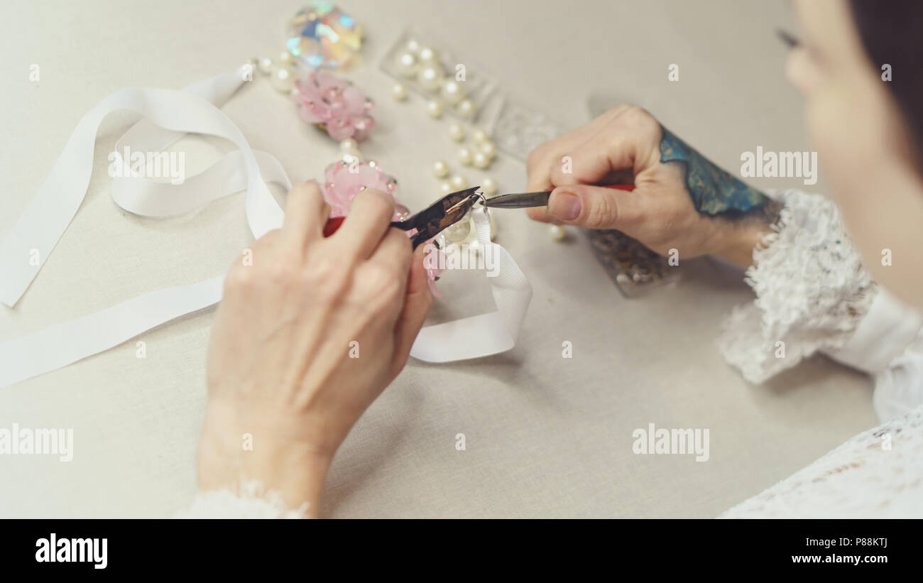 Girl fashion designer makes jewelry. Shooting close-up. She makes a ...