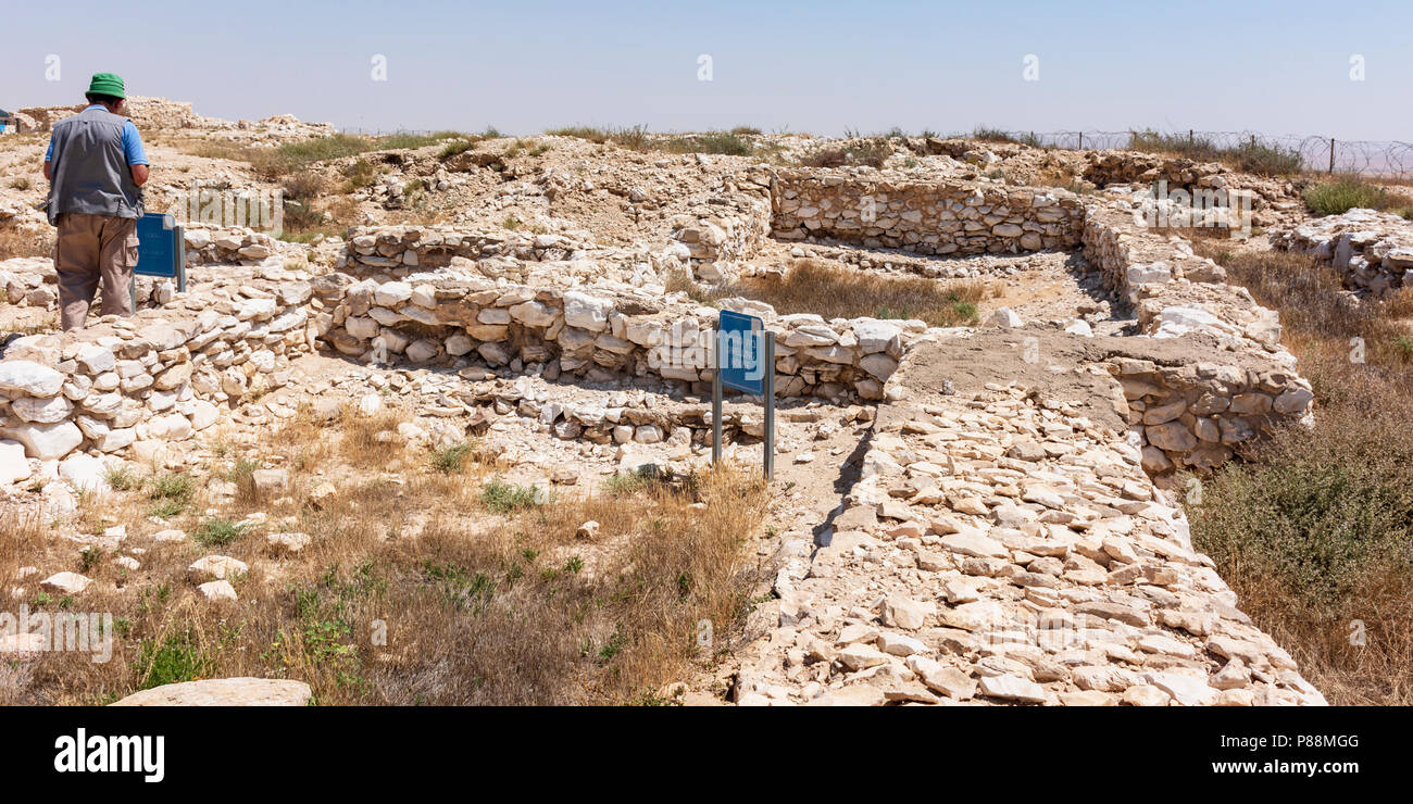 a tourist examines the stone dwellings in the ancient canaanite city at ...