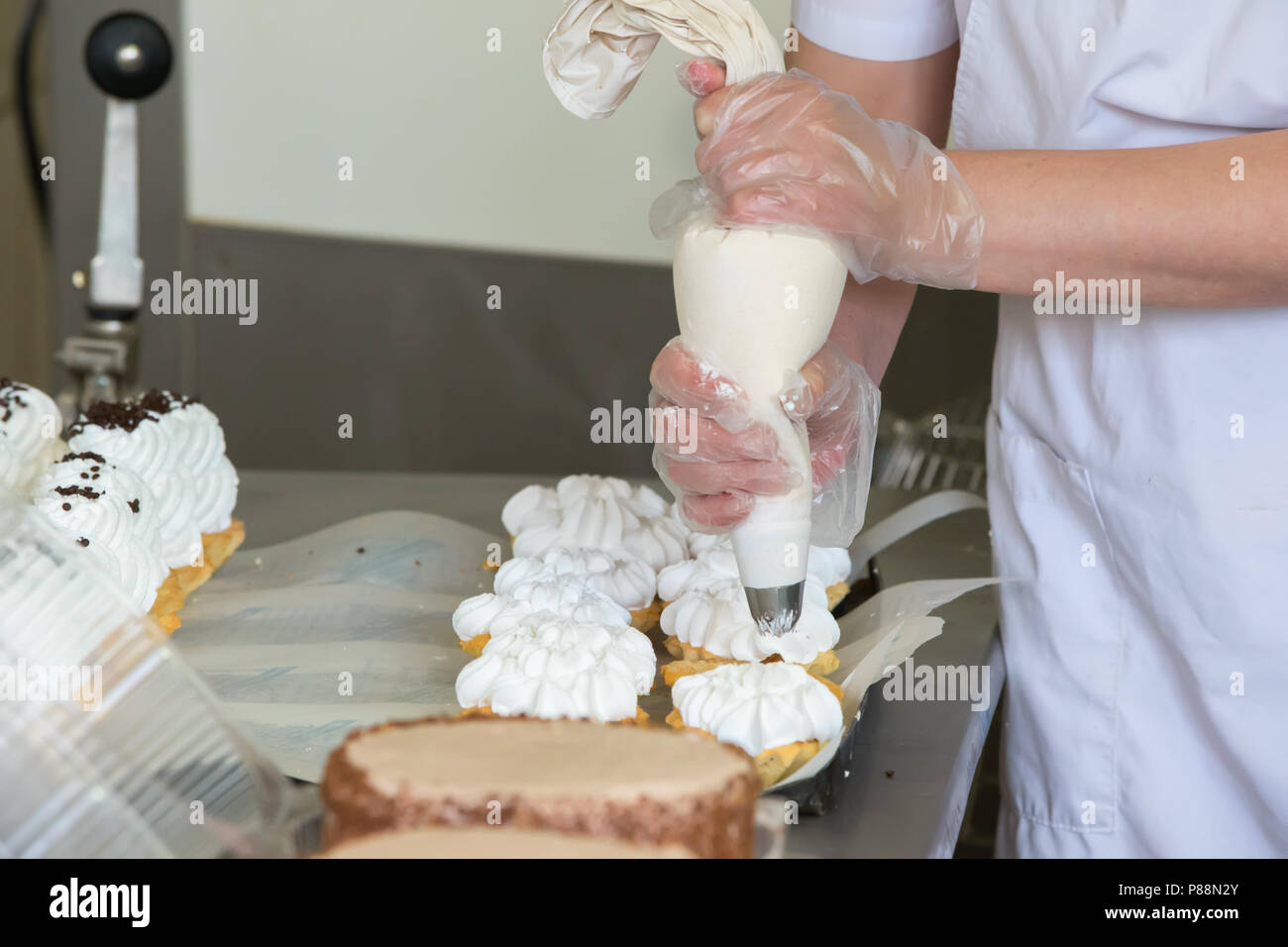Cooking and decorating a cake. A sweet white cream is squeezed out from ...