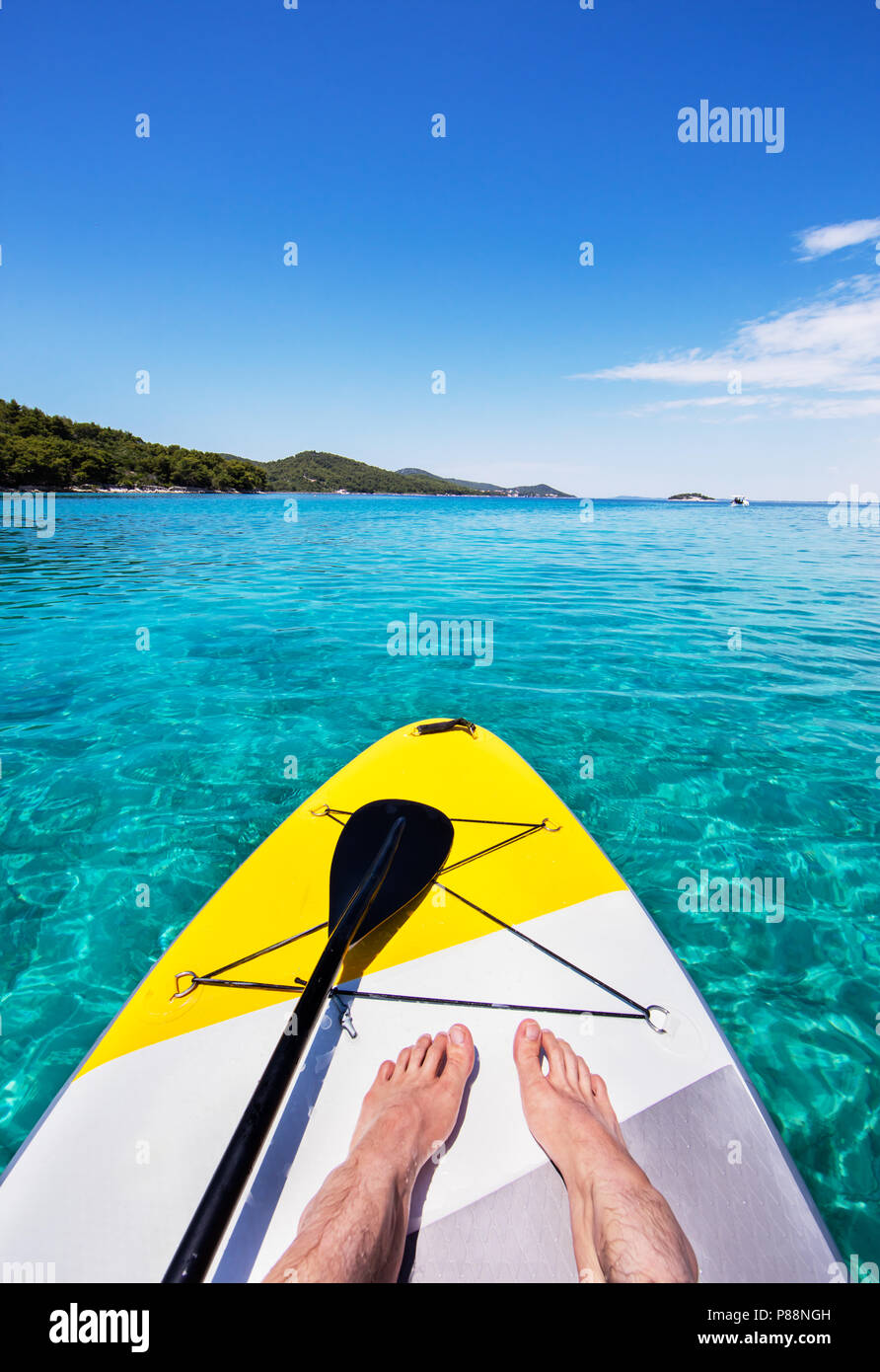 Detail of young man legs on paddleboard. Paddleboarding is the modern ...