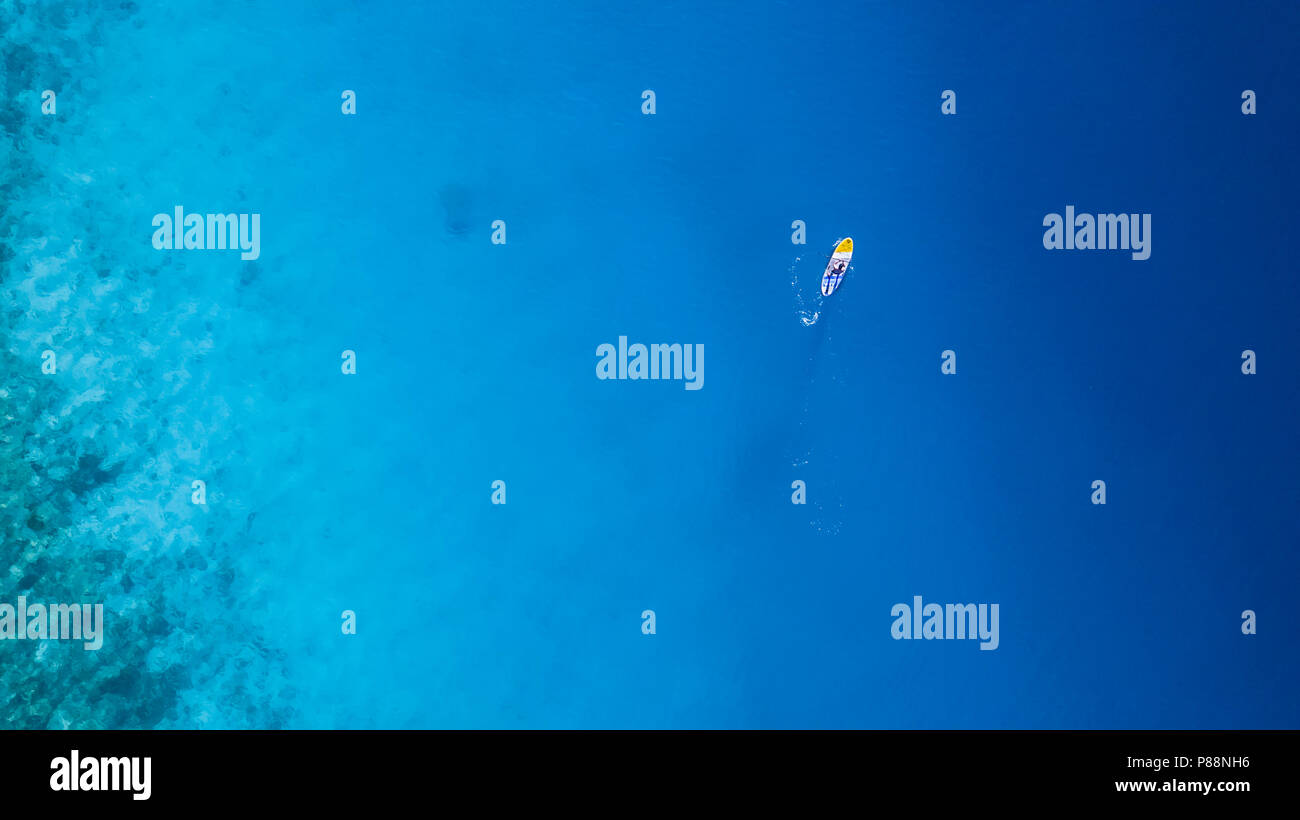 Aerial view of young man riding paddleboard. Paddleboarding is the ...