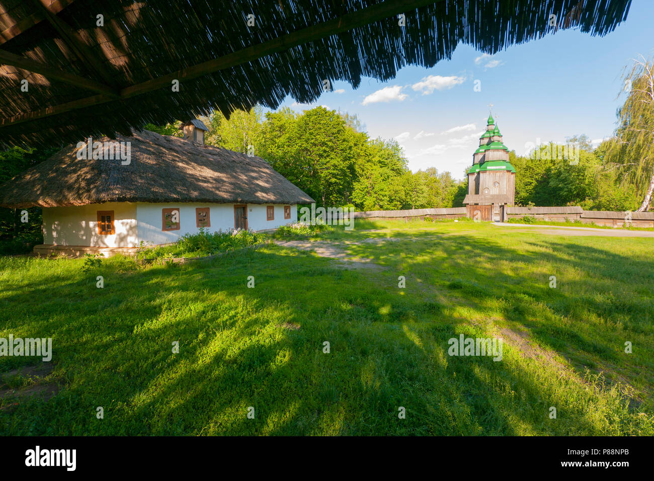 A large old Ukrainian hut on the background of a wooden church in the ...