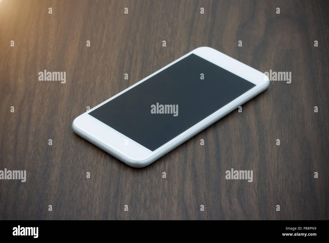 Smart phone with blank screen lying on wooden table- sunlight filter ...