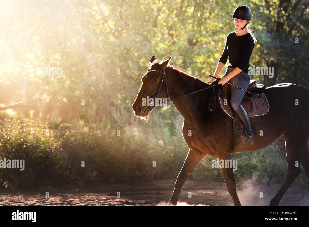 Young pretty girl - riding a horse with backlit leaves behind Stock ...