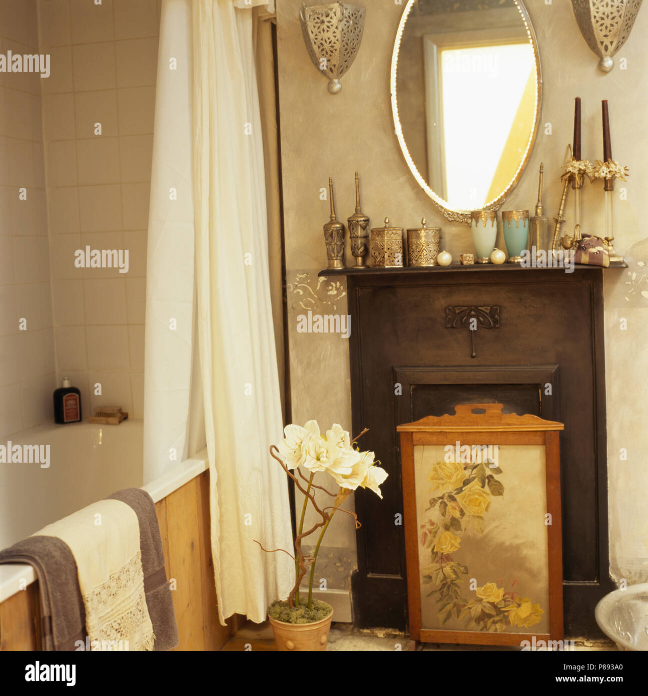 Oval mirror above small cast-iron fireplace with Victorian firescreen ...