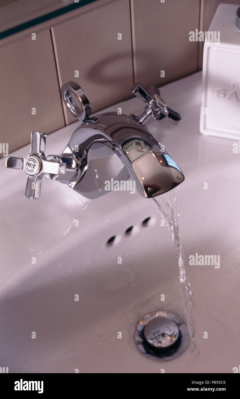 Close-up of chrome tap pouring water into white porcelain basin Stock ...