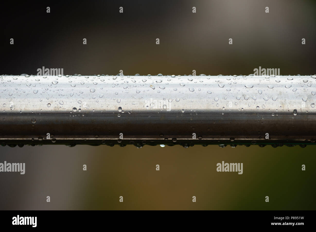 Horizontal wet stainless steel tube. Drops of rainwater on a metal ...