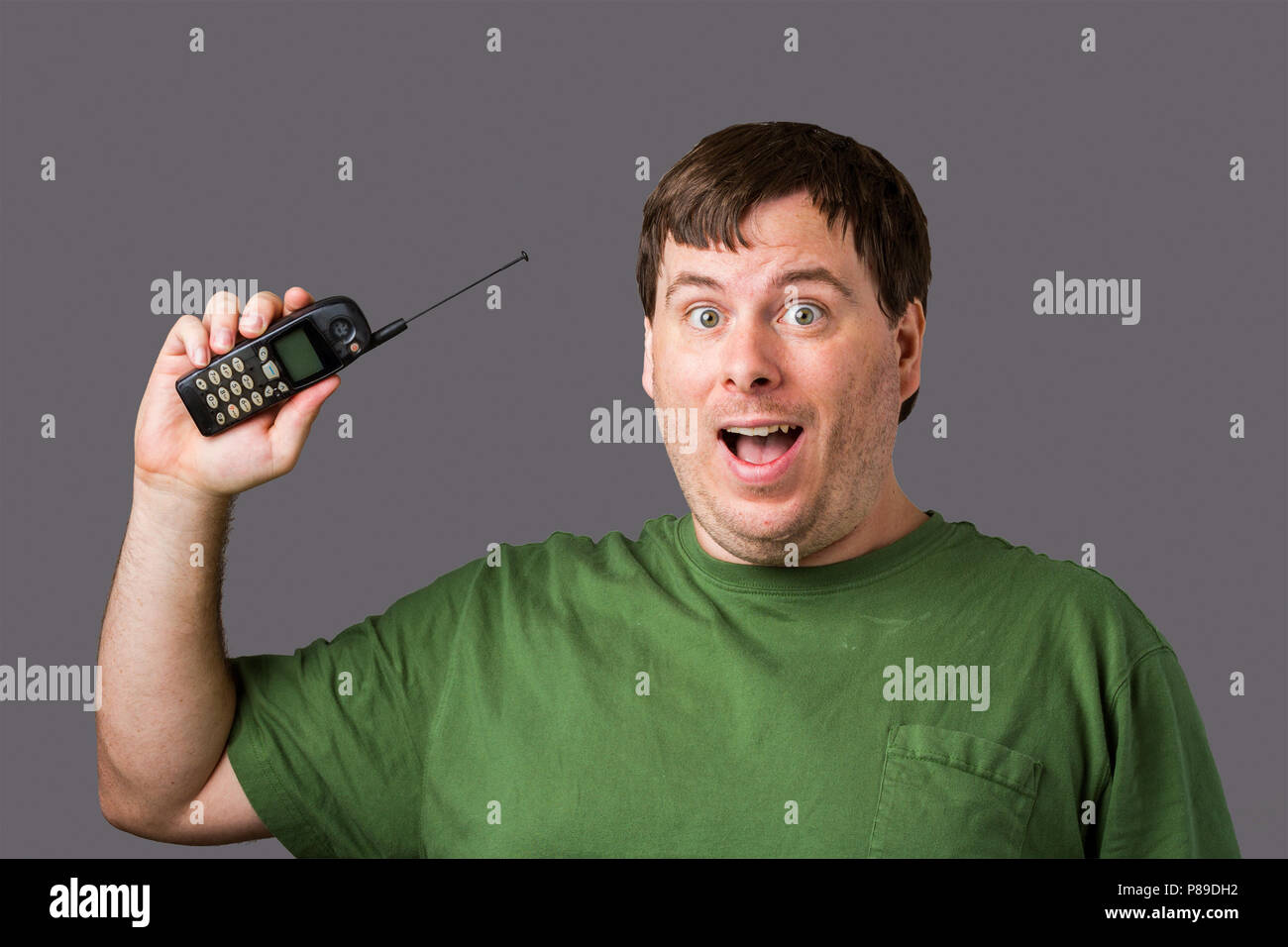 Man holding up his retro old school cell phone and is very happy. This ...