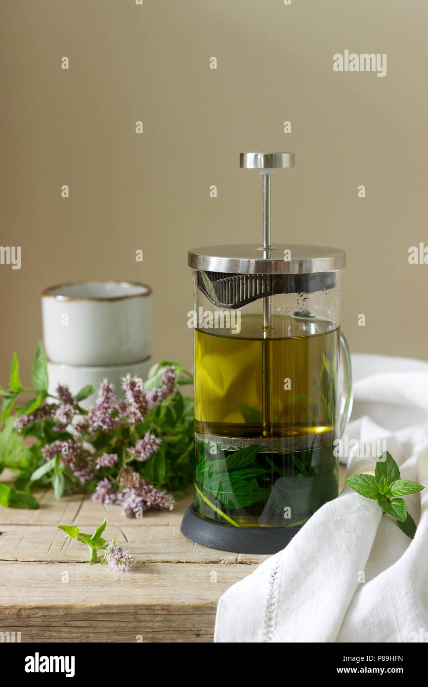 Mint tea in a clear glass teapot, mint leaves and tea cups. Selective ...