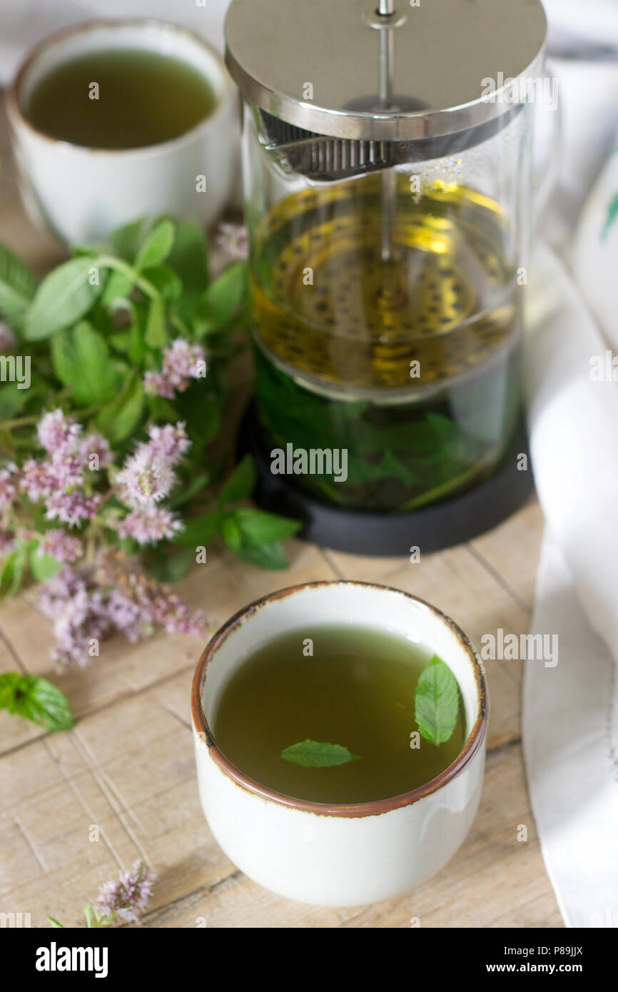 Mint tea in a clear glass teapot, mint leaves and tea cups. Selective ...