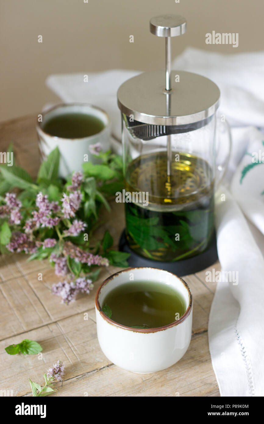 Mint tea in a clear glass teapot, mint leaves and tea cups. Selective ...