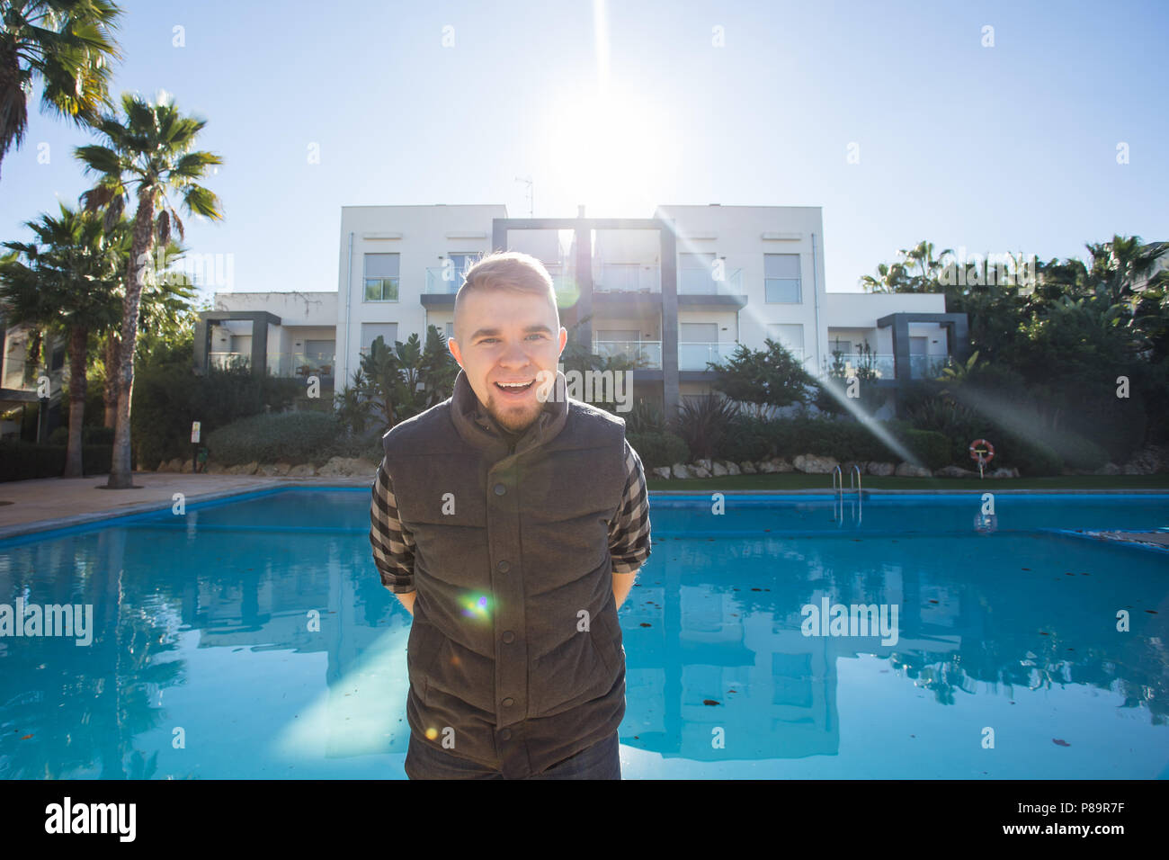 Man posing against pool background putting his hands behind his back ...