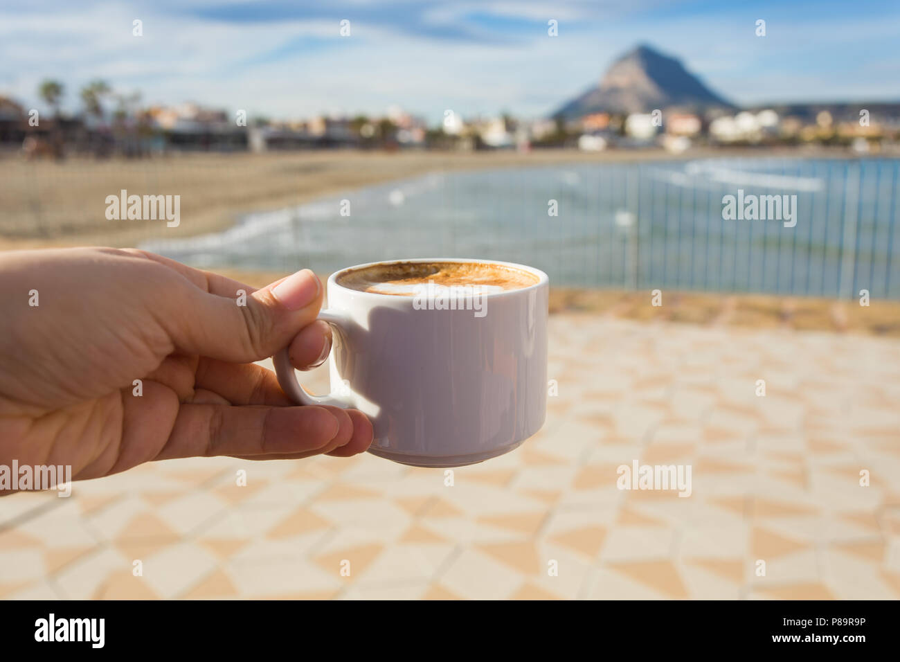 Cup of coffee in hand on the background of a beautiful beach Stock ...