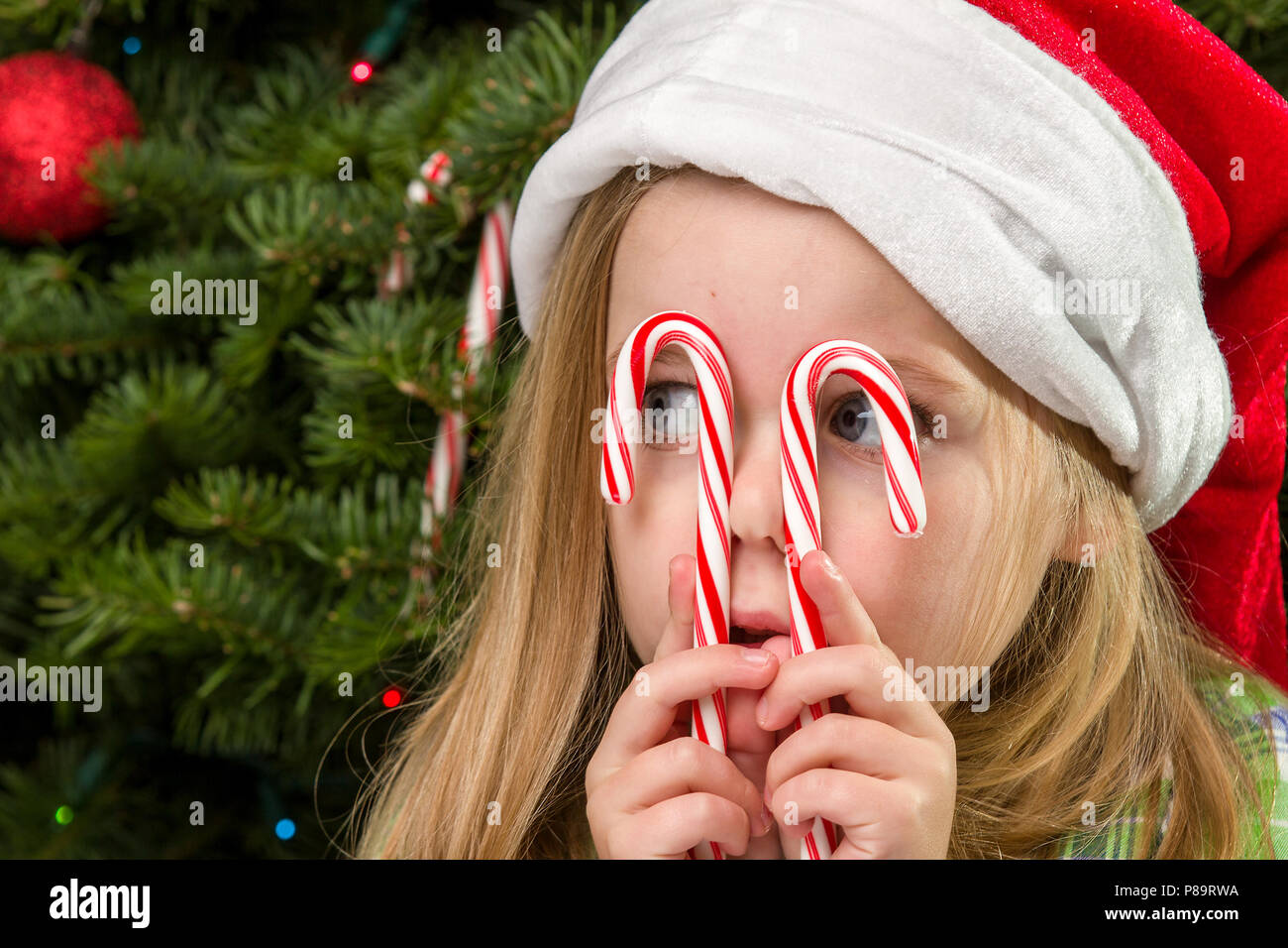 Child is holding up candy canes to her eyes making funny faces Stock ...