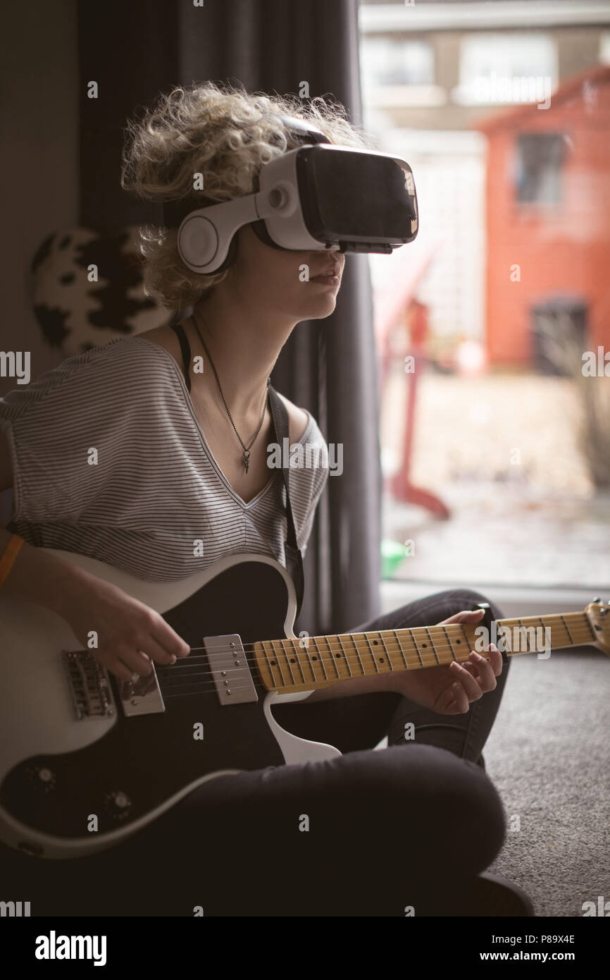 Young woman using virtual headset while playing guitar Stock Photo - Alamy