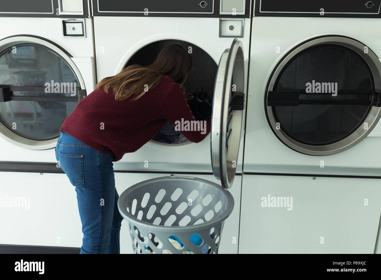 Woman doing laundry in laundromat Stock Photo - Alamy
