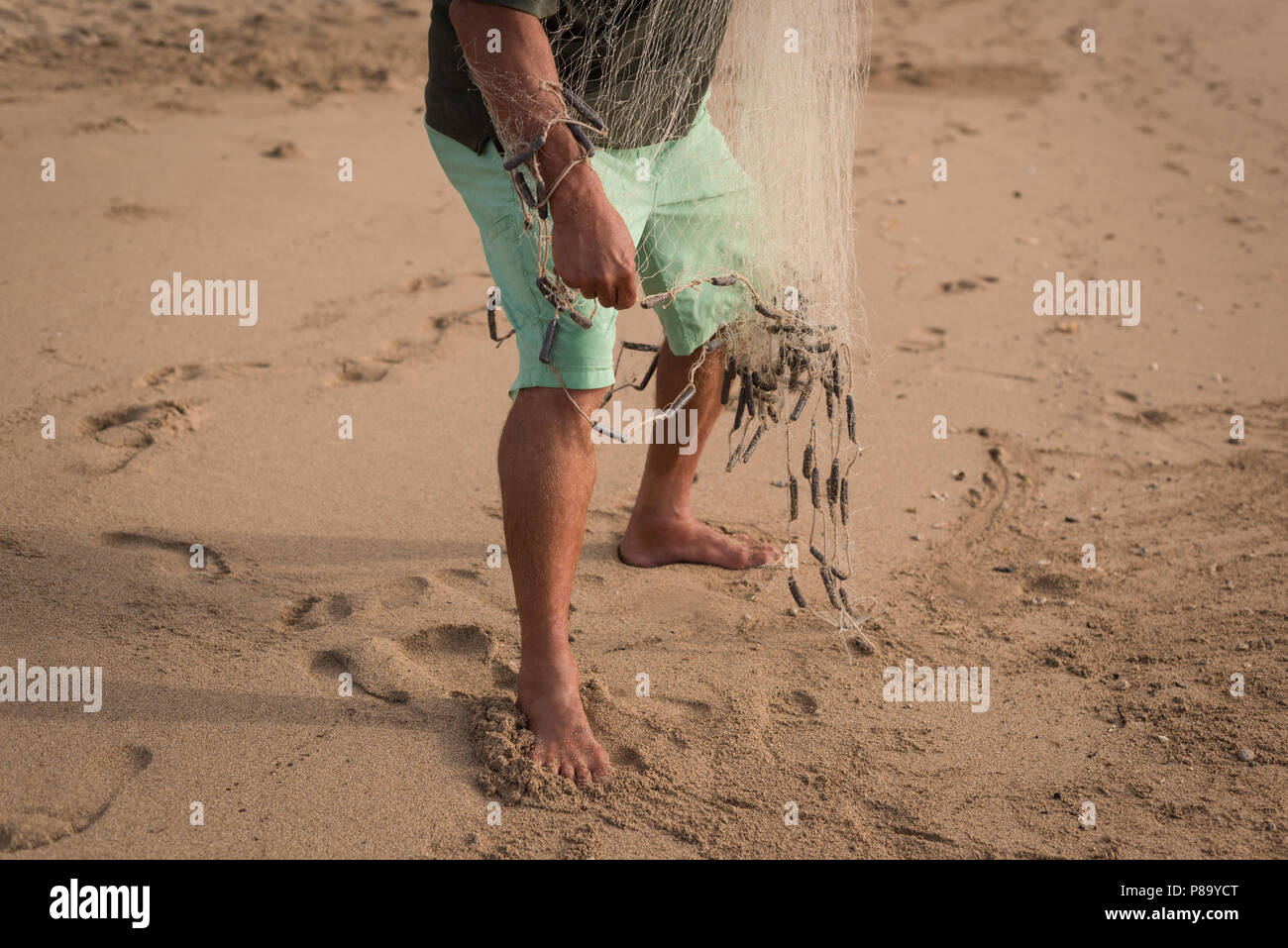 Fisherman holding fishing net on the beach Stock Photo - Alamy