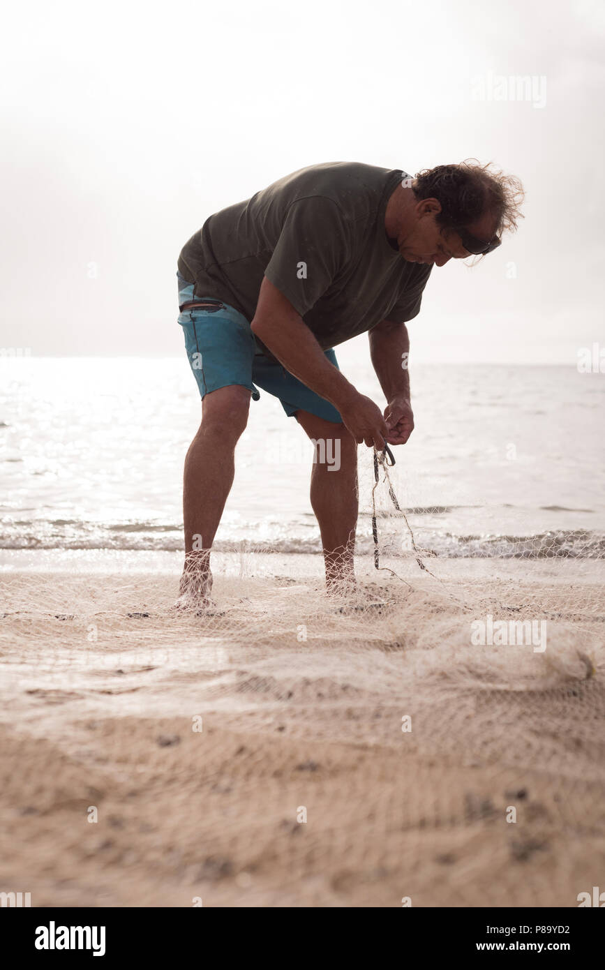 Fisherman holding fishing net on the beach Stock Photo - Alamy