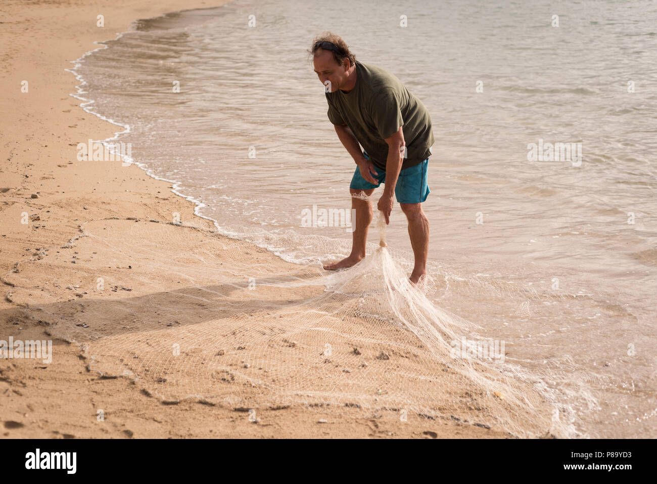 Fisherman holding fishing net on the beach Stock Photo - Alamy