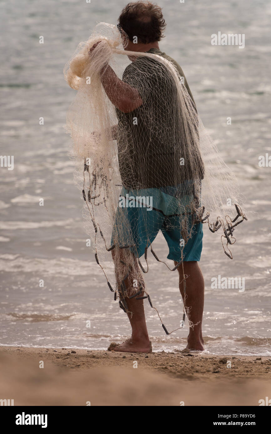 Fisherman holding fishing net on the beach Stock Photo - Alamy