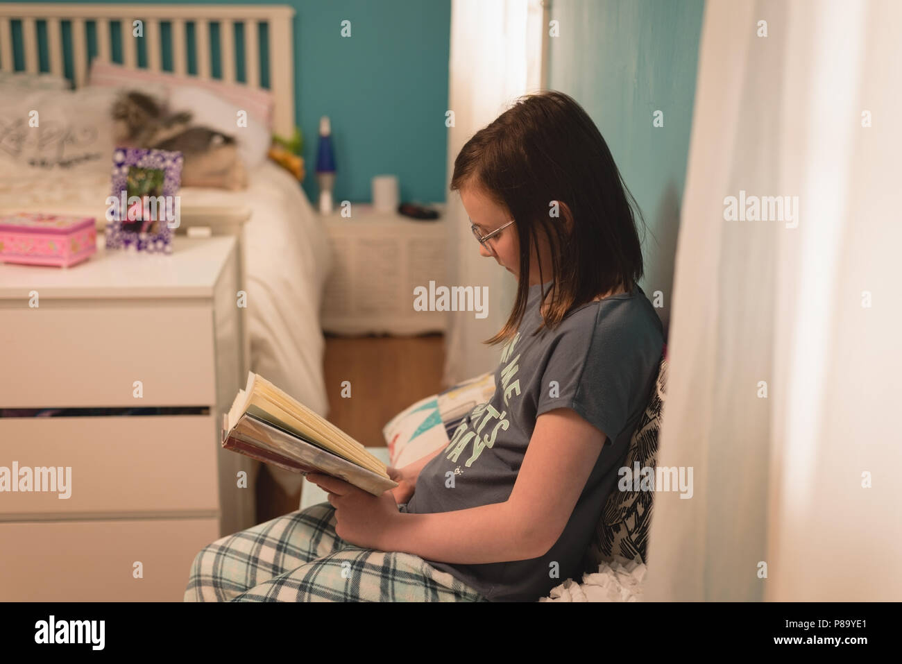Girl reading a book in bedroom Stock Photo - Alamy