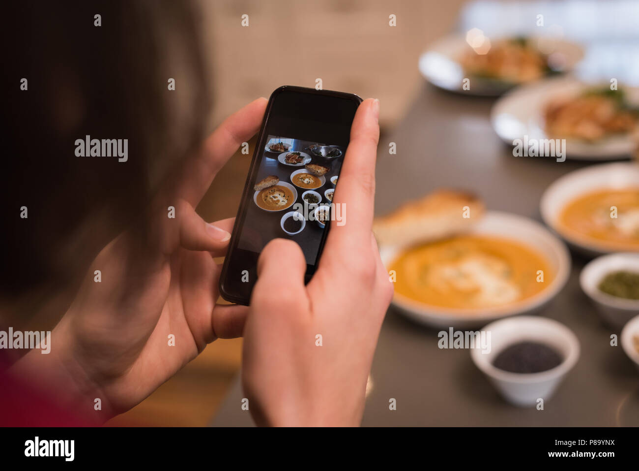 Woman clicking photo of food in kitchen Stock Photo - Alamy