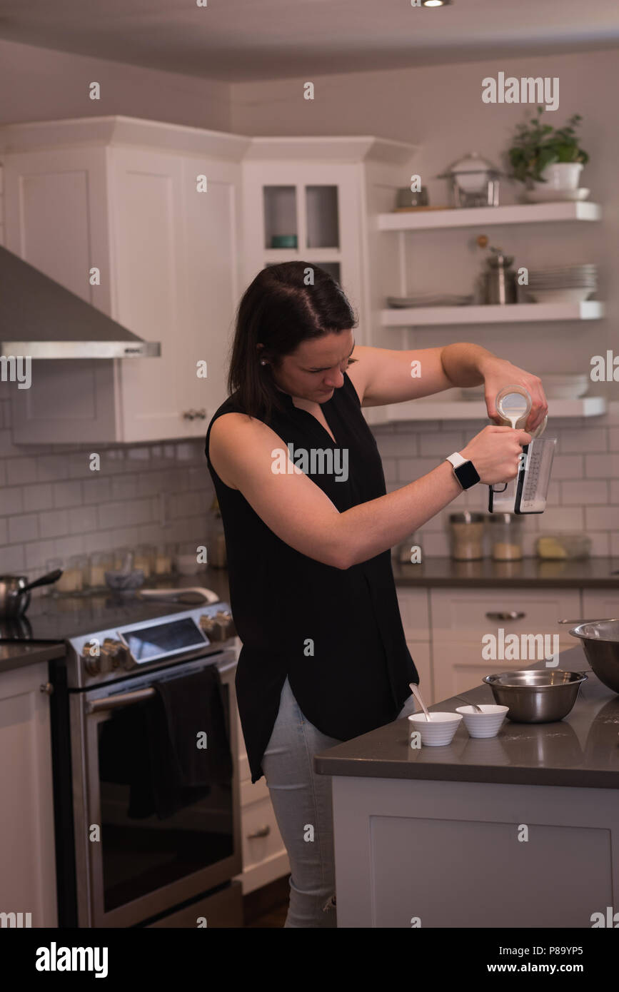 Woman pouring mug into jug in kitchen Stock Photo - Alamy