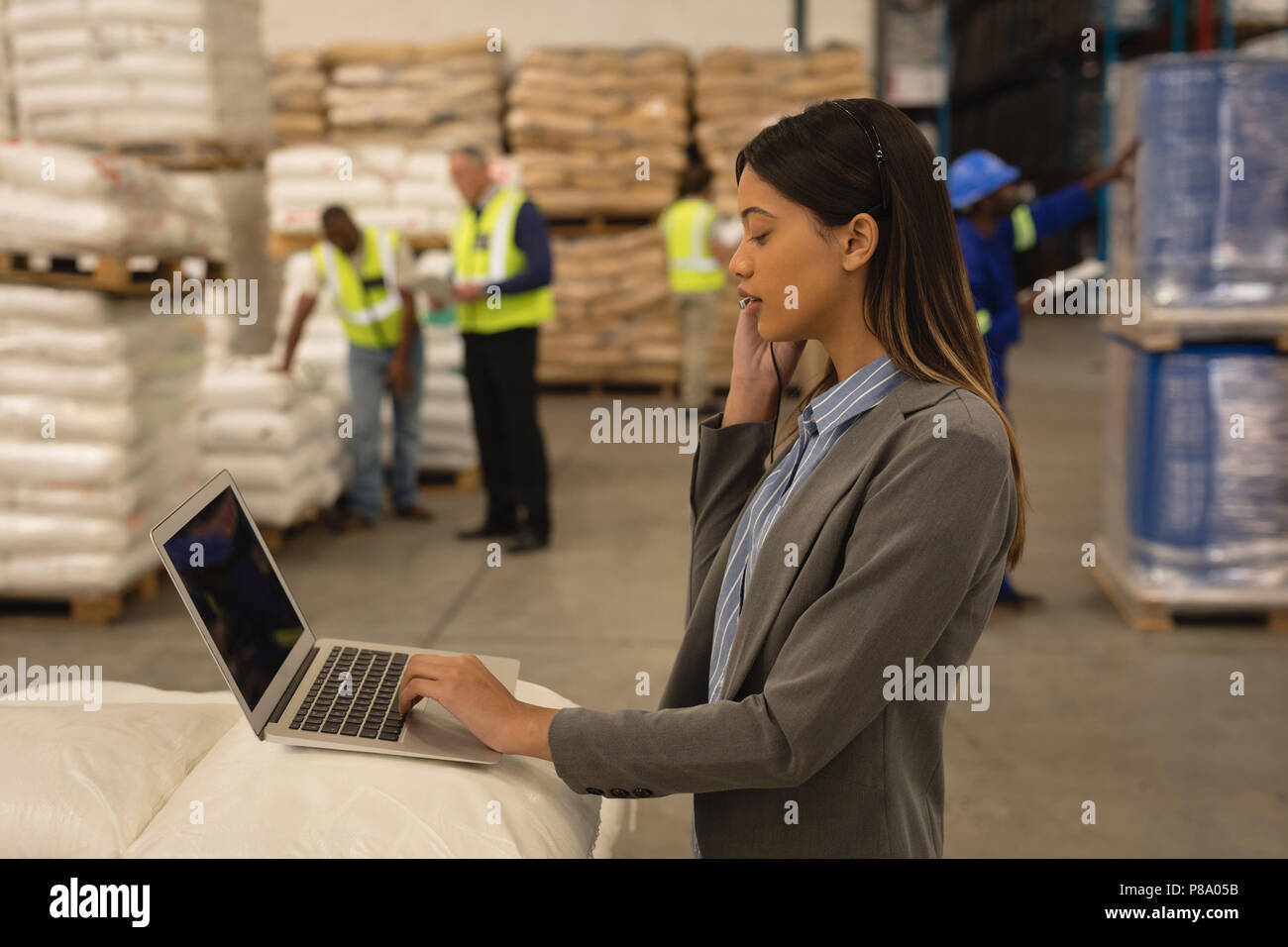 Female supervisor talking on mobile phone while using laptop Stock ...