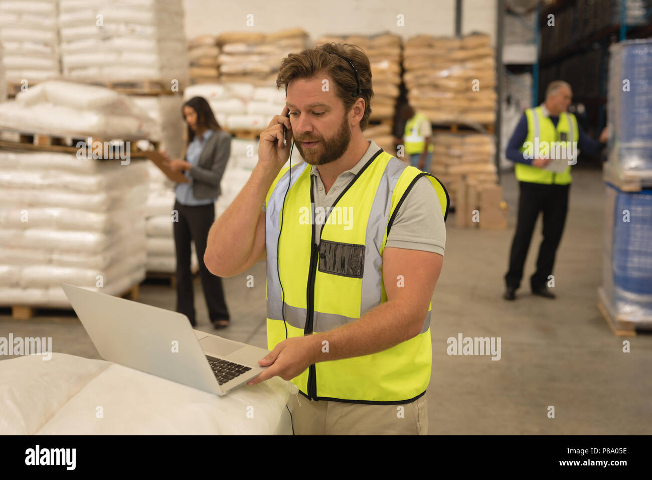 Male supervisor talking on mobile phone while using laptop Stock Photo ...
