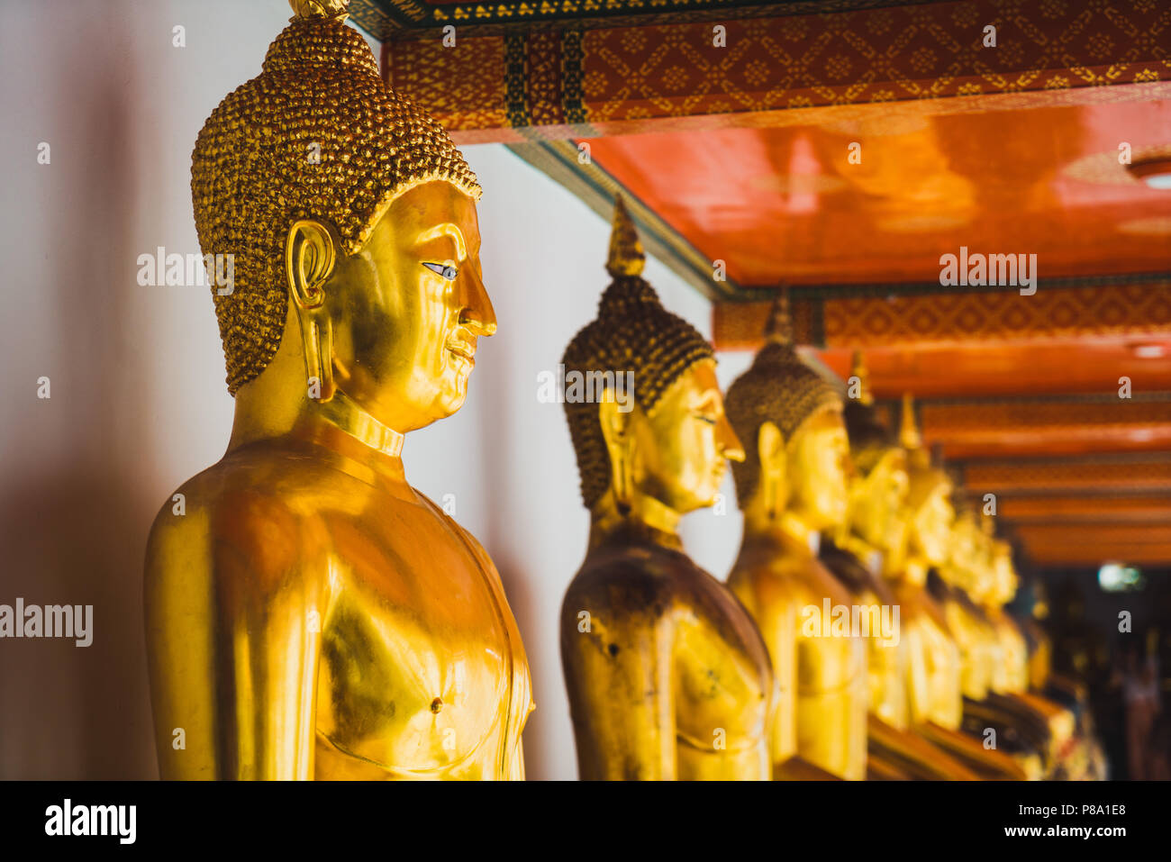 Row of golden religious statues in temple in Bangkok, Thailand Stock ...